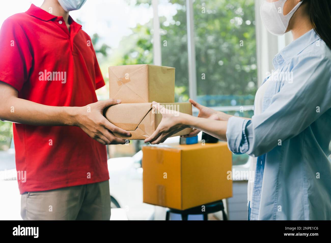 Asian delivery man wearing face mask in red uniform deliver service ...