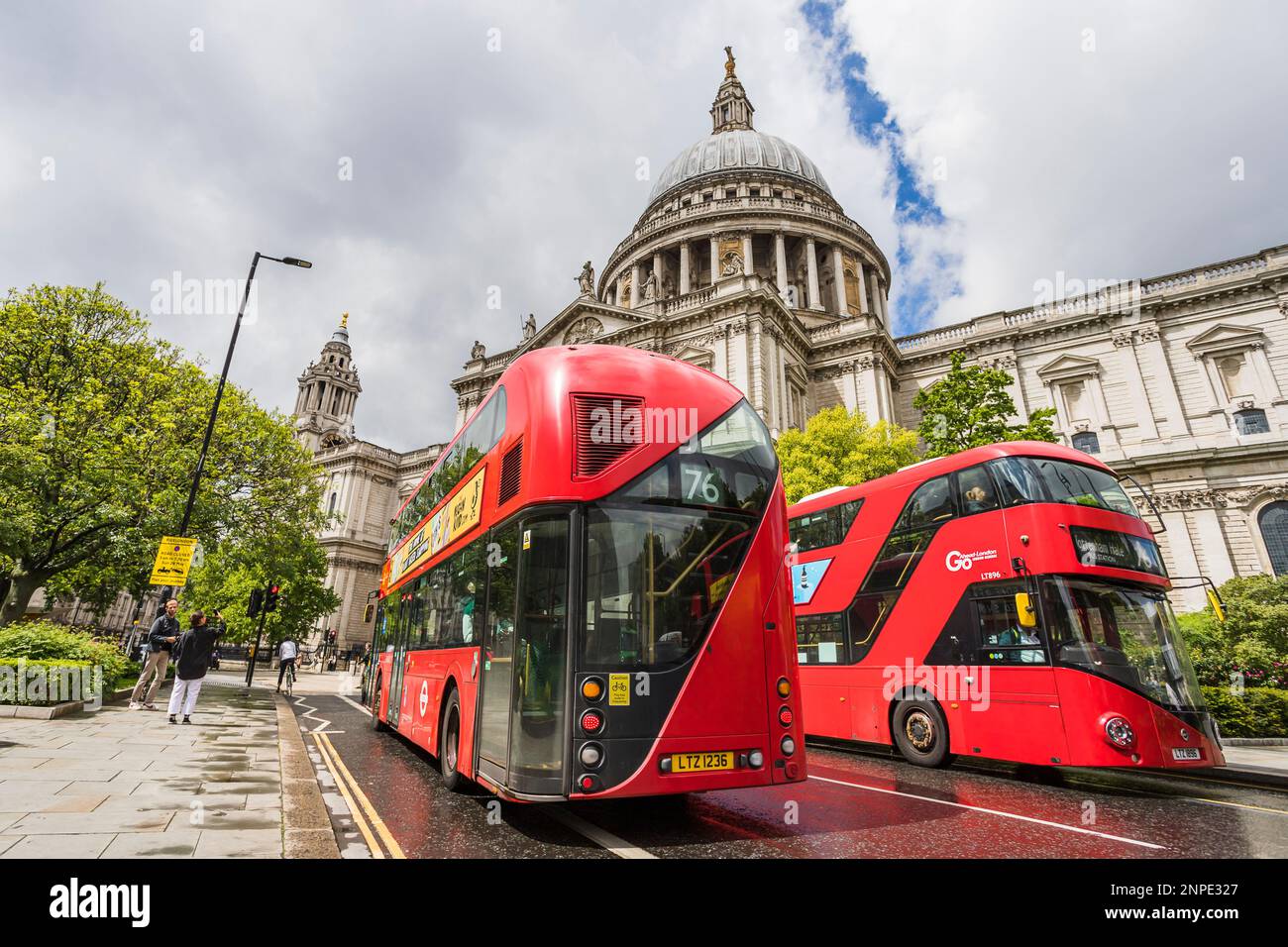A pair of vivid red London buses pass in front of St Pauls Cathedral in ...