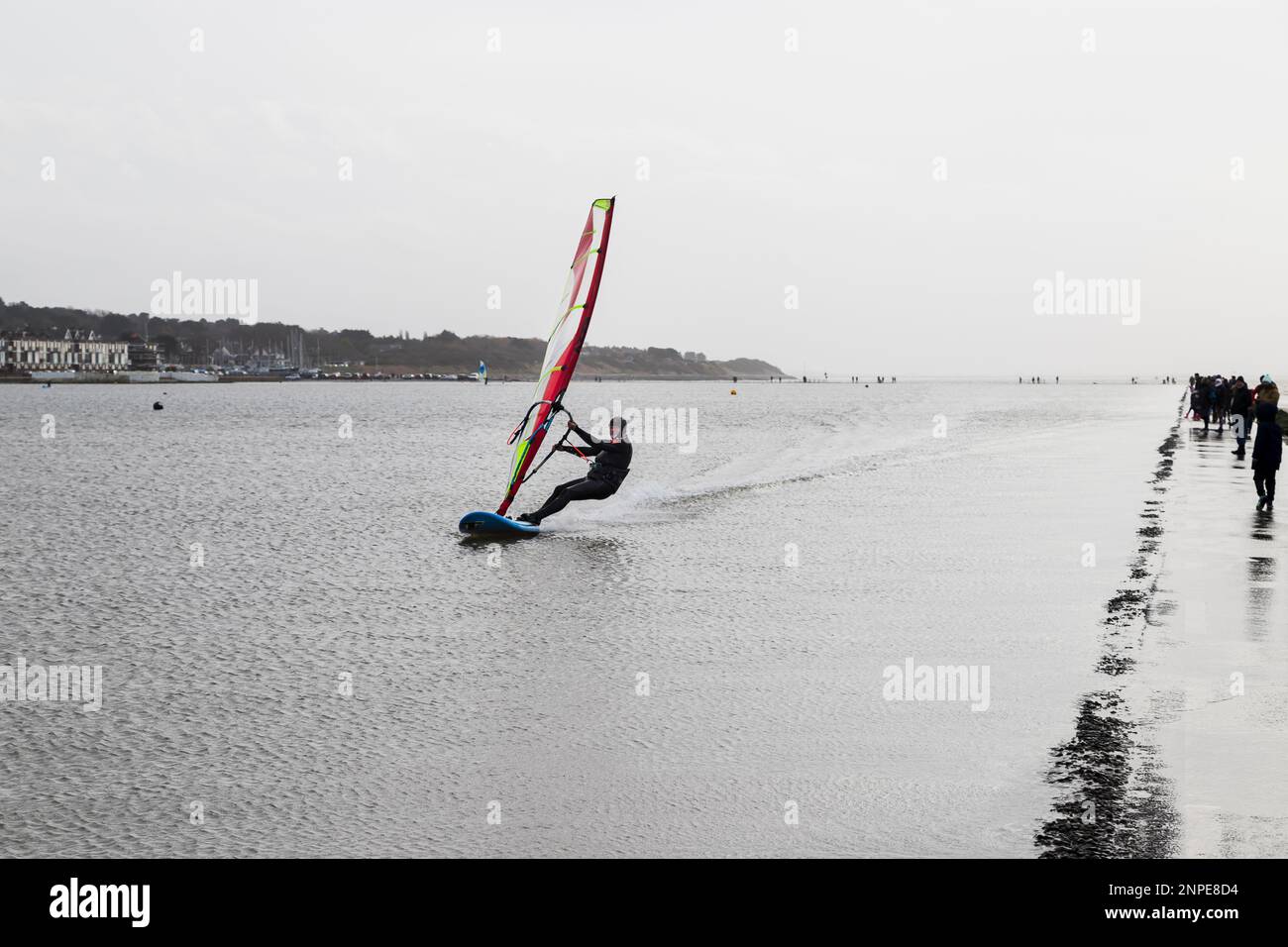 A wind surfer takes advantage of a windy day as he passes walkers at ...