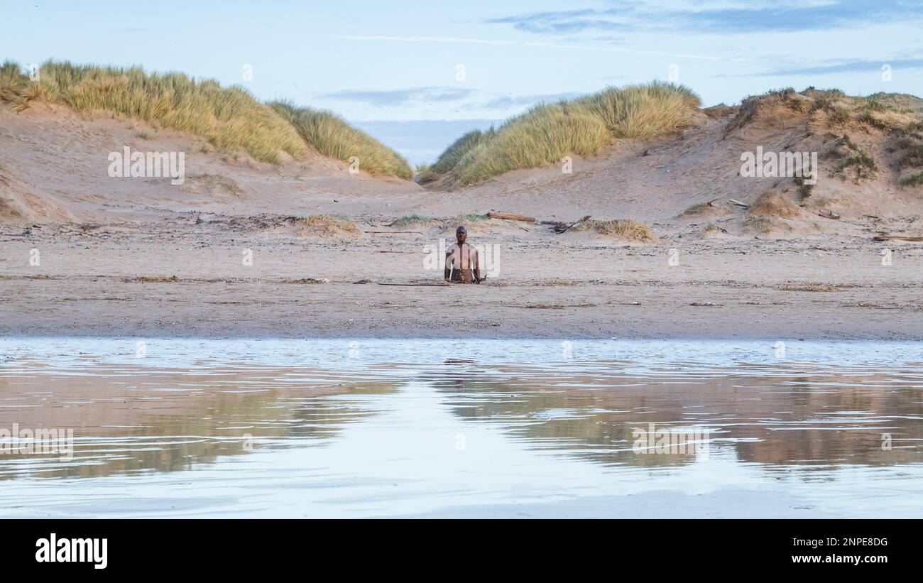 An Iron Man seen between the sand dunes on Crosby Beach Stock Photo - Alamy
