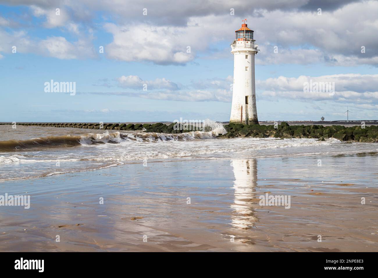 New Brighton Lighthouse reflects in the wet sandy beach on the edge of ...