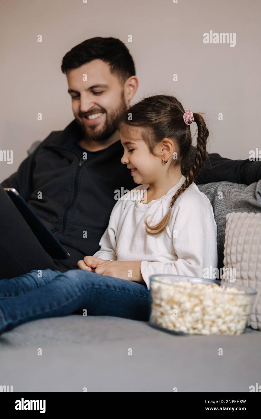 Adorable little girl watching cartoons on table with her father ...