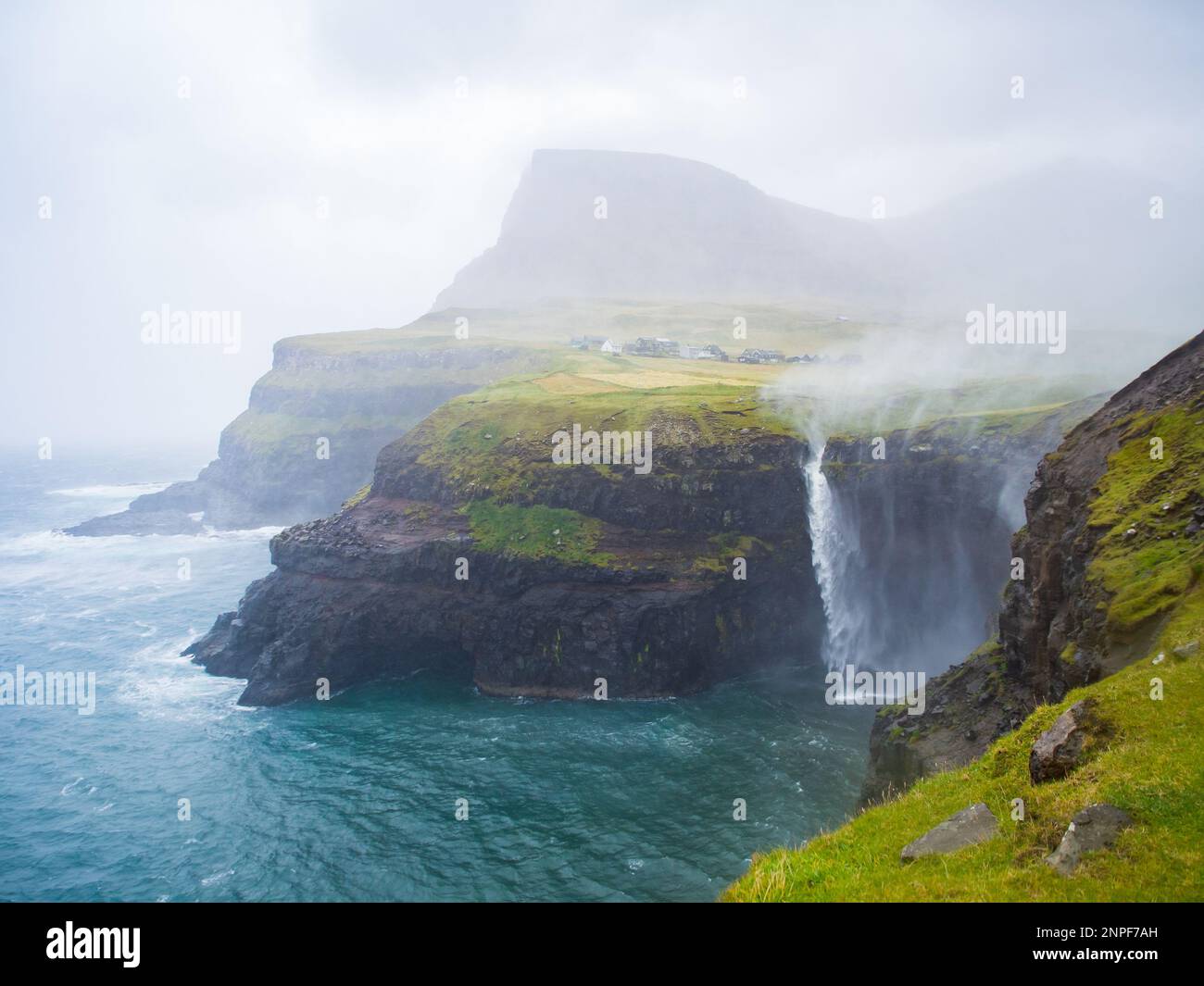 Waterfall Gasadalur falling into the ocean during strong wind in rainy ...
