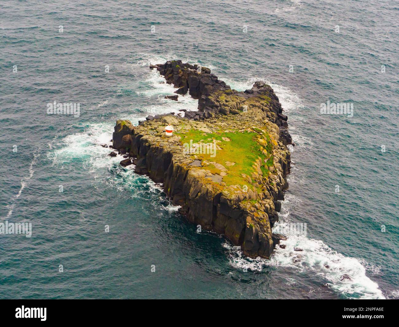A tiny island in the shape of a lighthouse seen from a helicopter ...