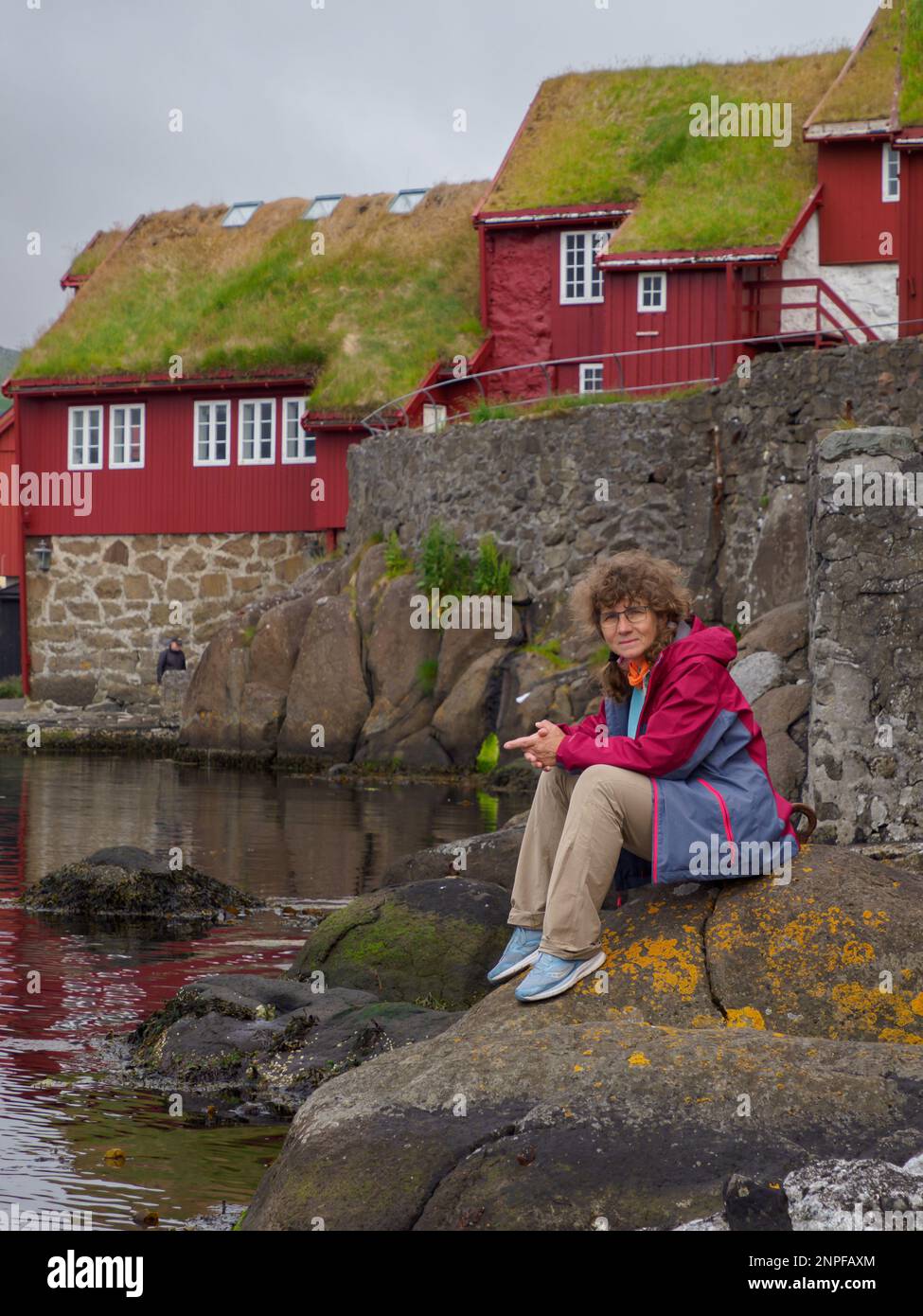 Tórshavn, Faroe Islands - July, 2021: Tourist sitting on the rock and ...