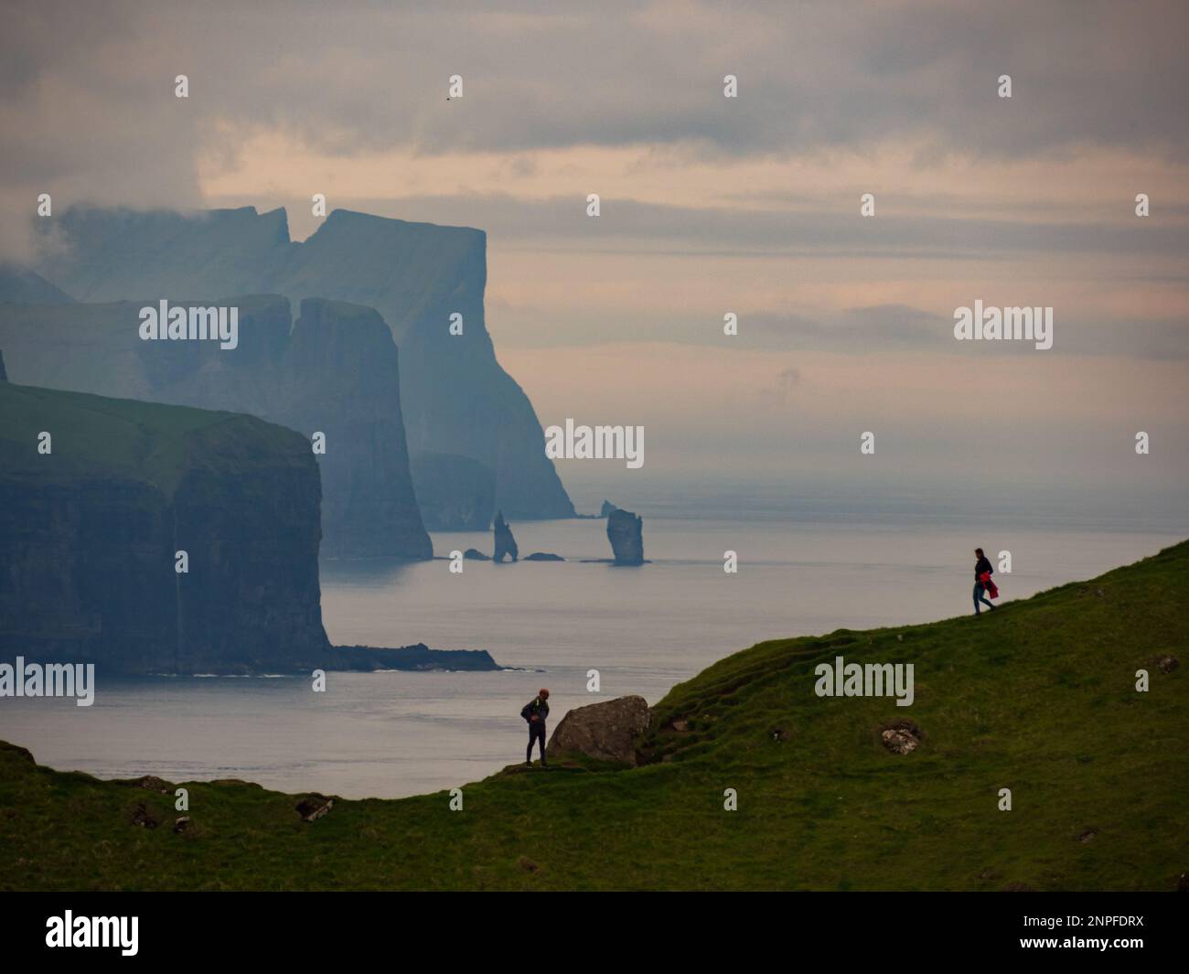 Tourists silhouettes on background of Risin og Kellingin rocks and ...