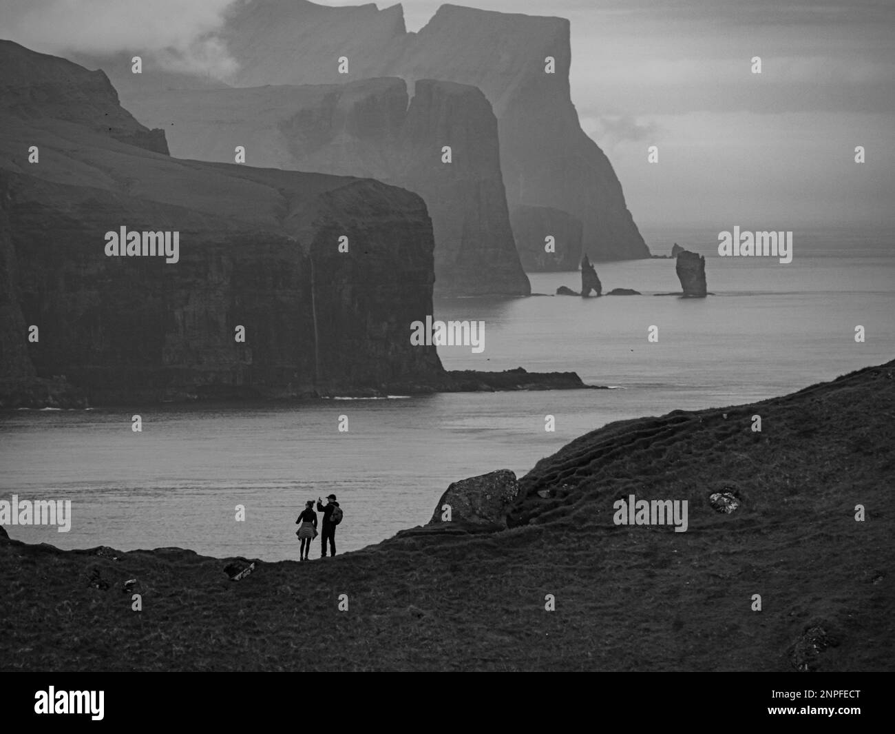 Tourists silhouettes on background of Risin og Kellingin rocks and ...