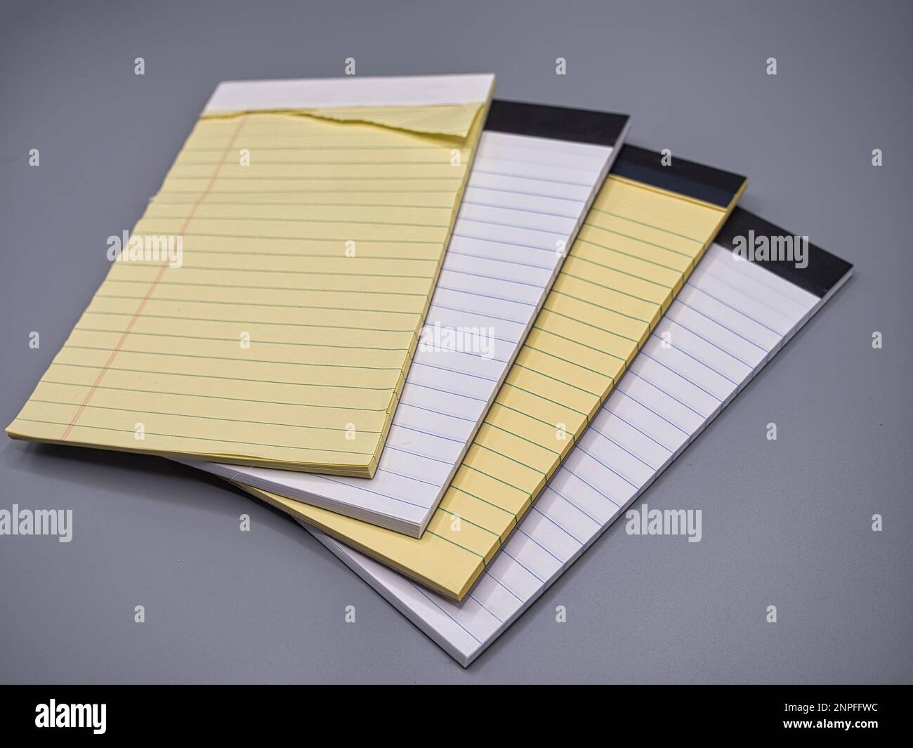 Yellow and white legal pads laid out on a plain gray background. This ...