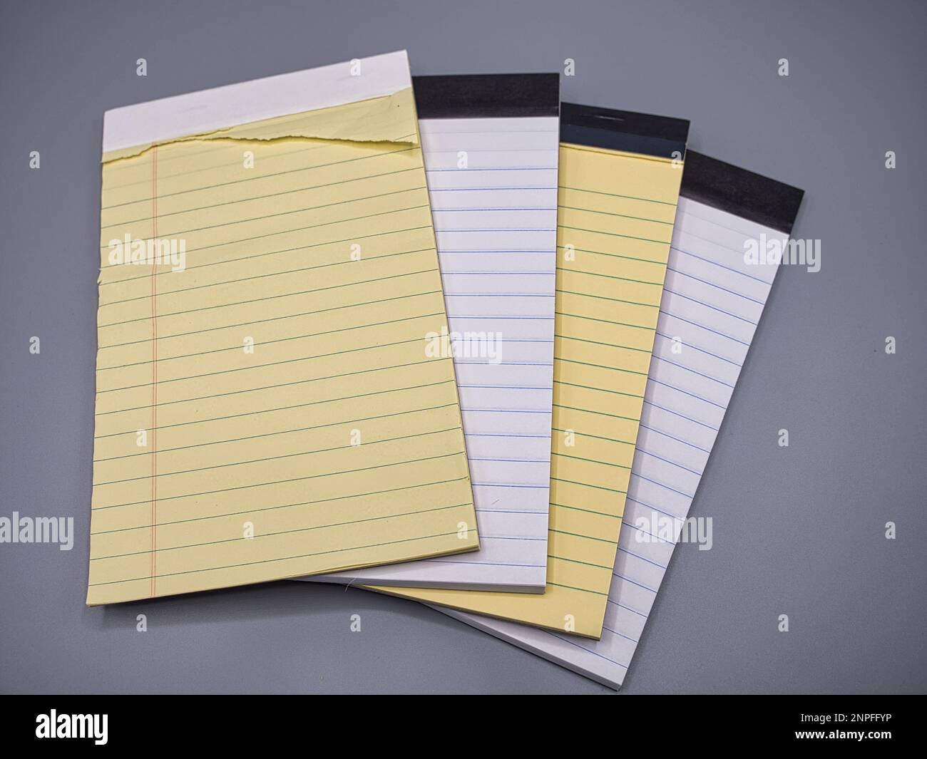 Yellow and white legal pads laid out on a plain gray background. This ...