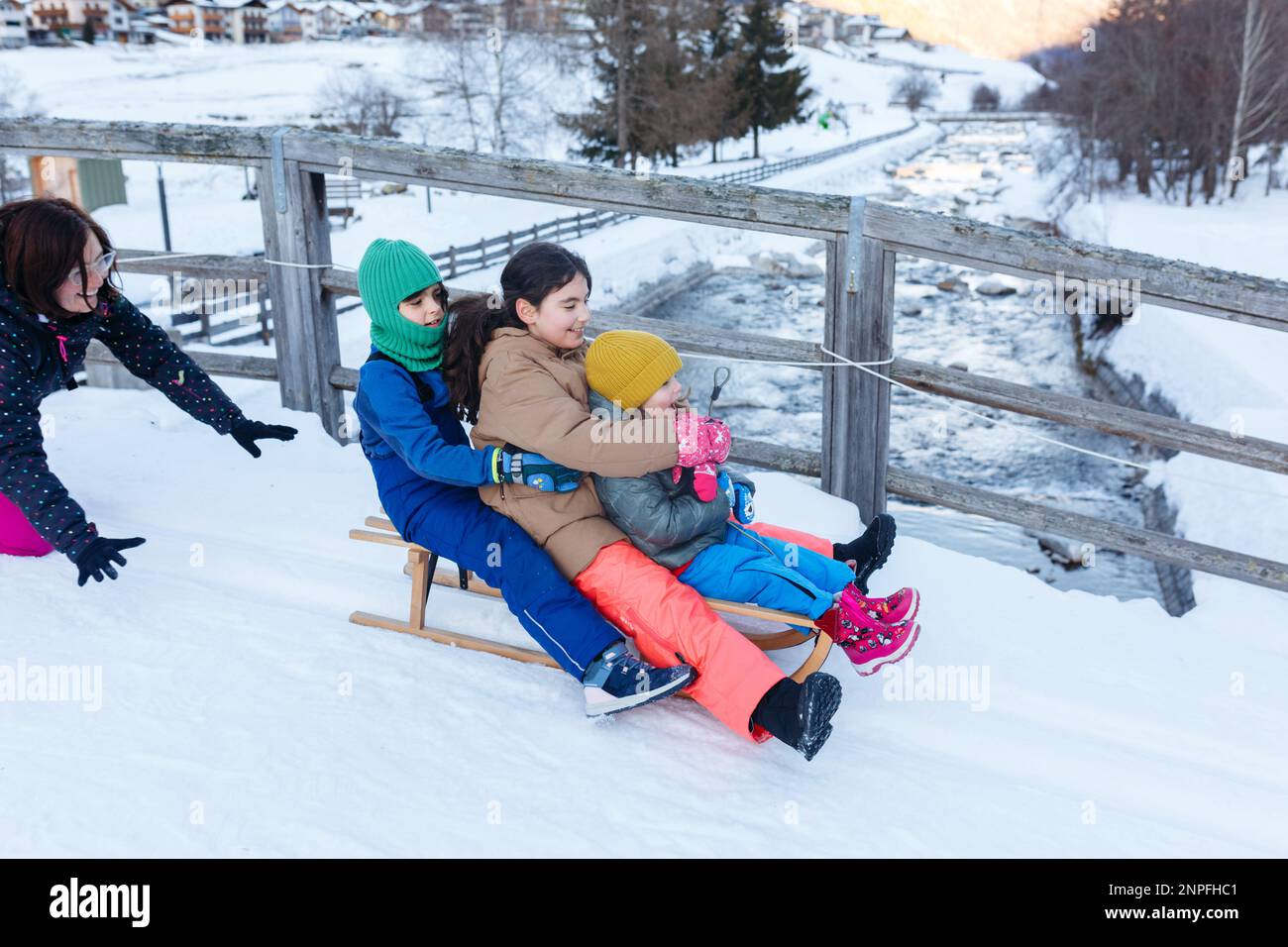 mother pushing wooden sled with her three daughters on snow slope Stock ...