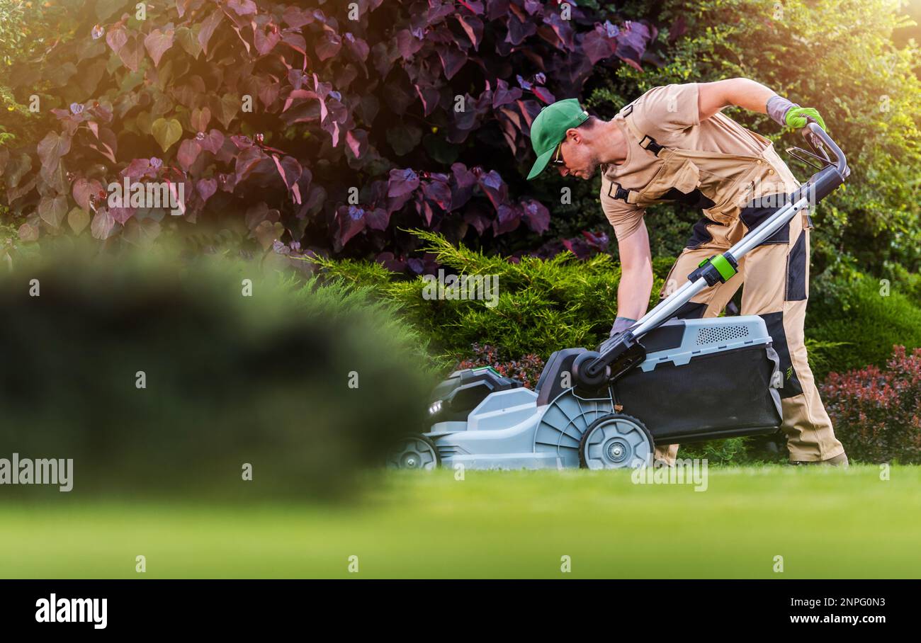 Caucasian Garden and Landscaping Worker Mowing Backyard Lawn Using ...