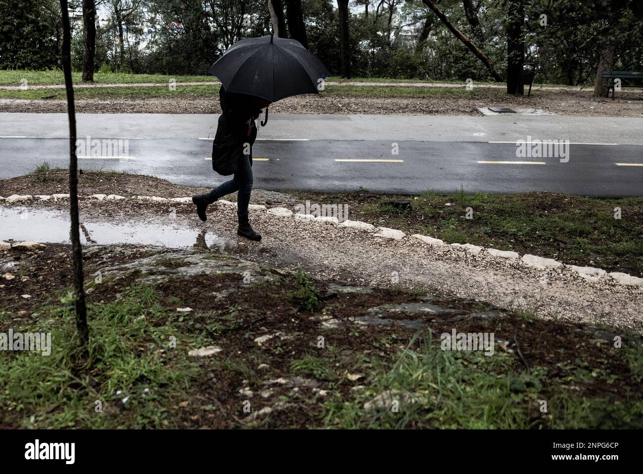 A woman walks with her umbrella as rain falls in Split, Croatia on ...