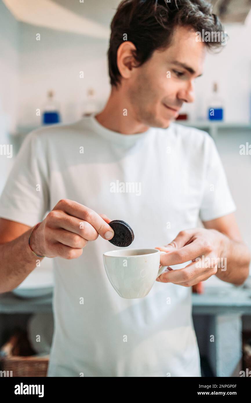 Young man dipping a black sandwich biscuit into milk Stock Photo - Alamy