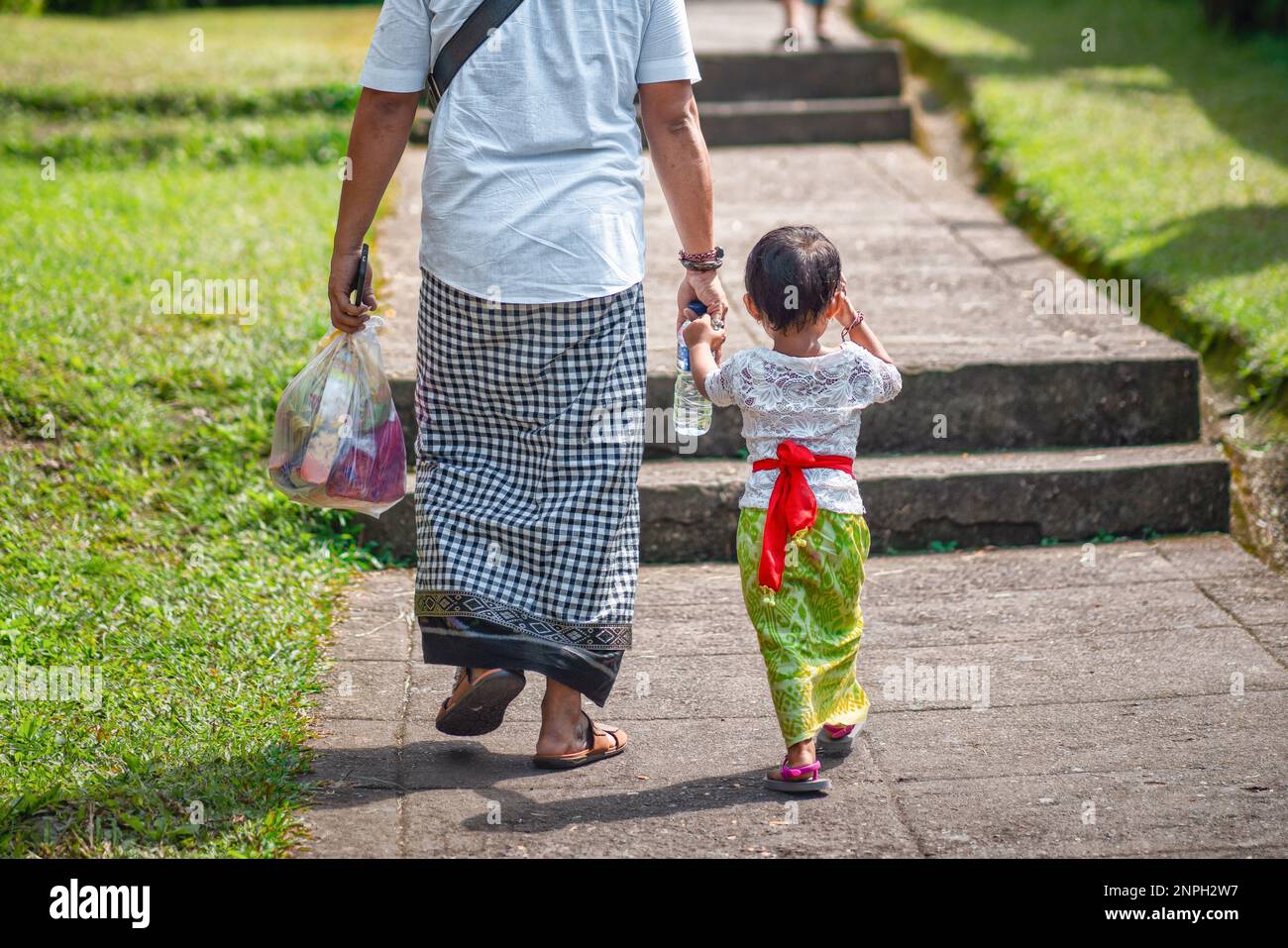 Father and son hold hands and walk together along the path. Indonesian ...
