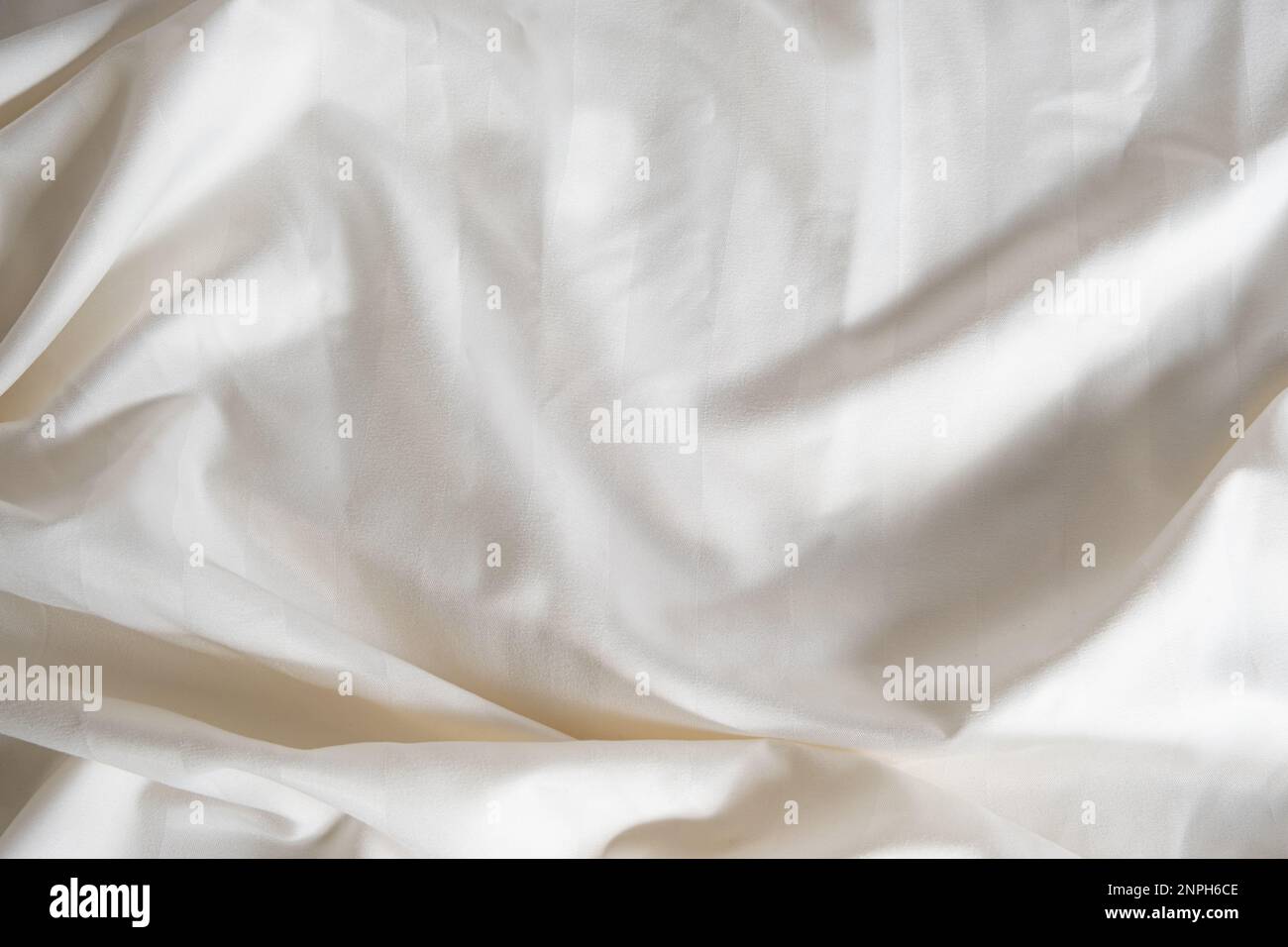 Satin crumpled fabric of light milky color, top view. Natural bed linen ...