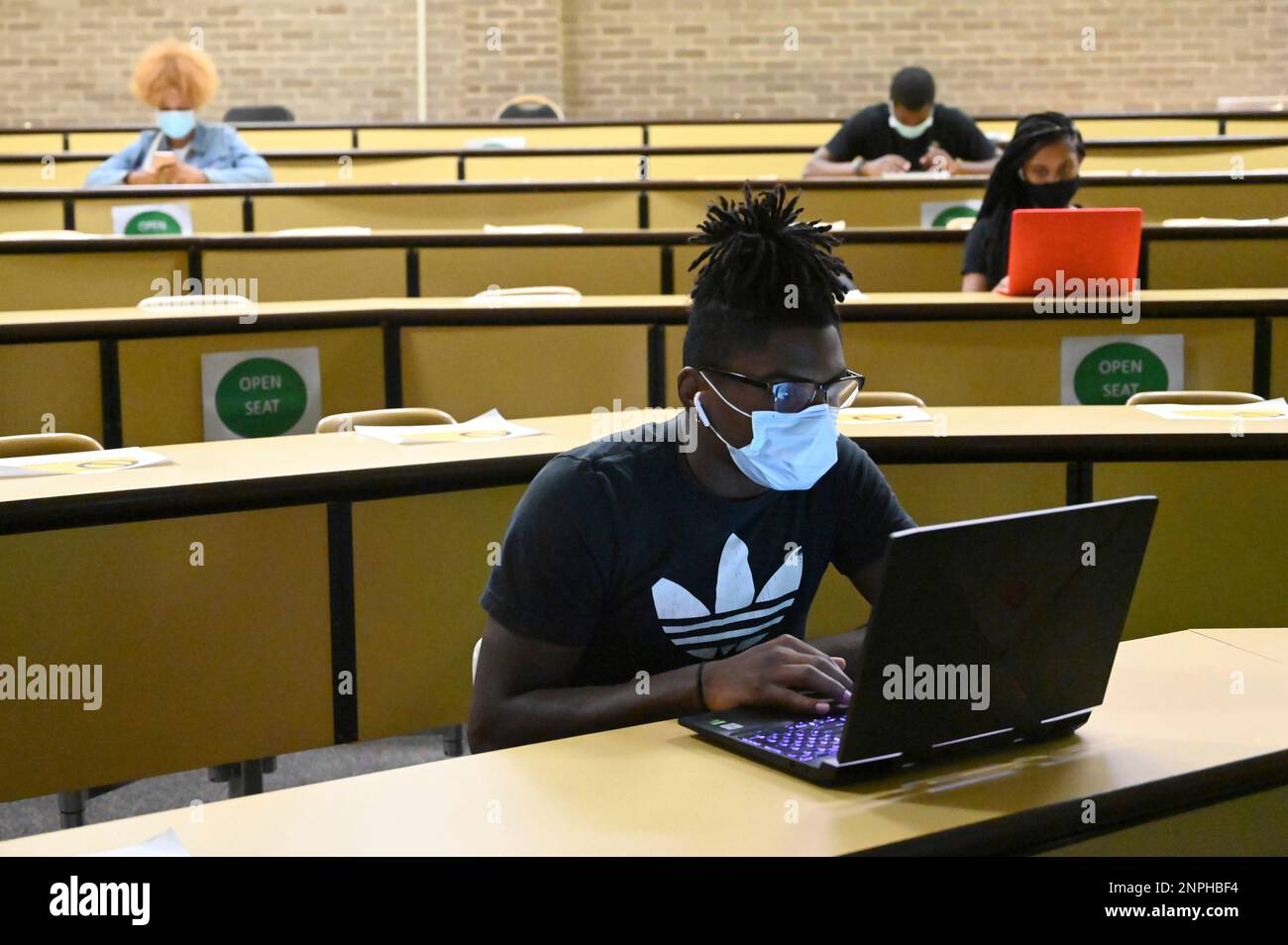 Jaheem Williams works on his laptop, with classmates spaced out behind ...