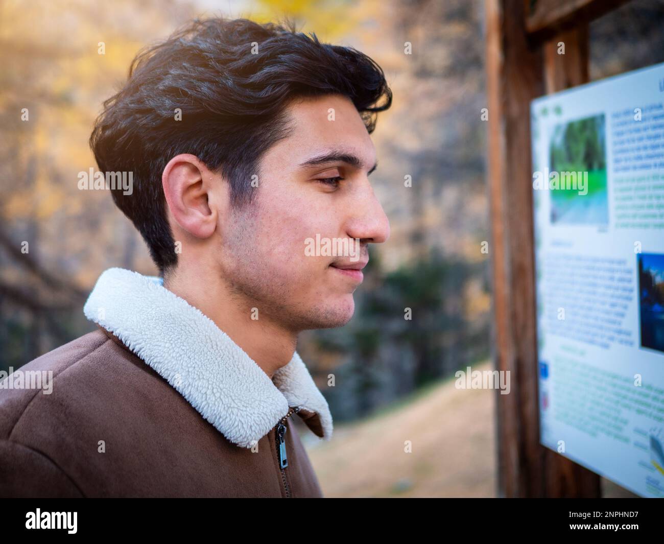 Young man reading sign in public park Stock Photo - Alamy