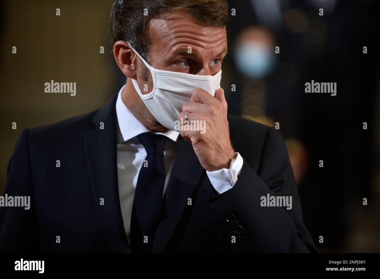 French President Emmanuel Macron adjusts his mask during a ceremony to ...