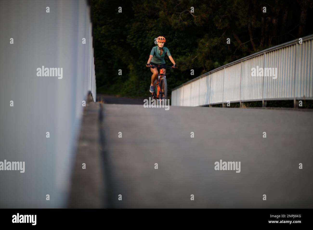 Pretty, young woman with her mountain bike going for a ride past the ...