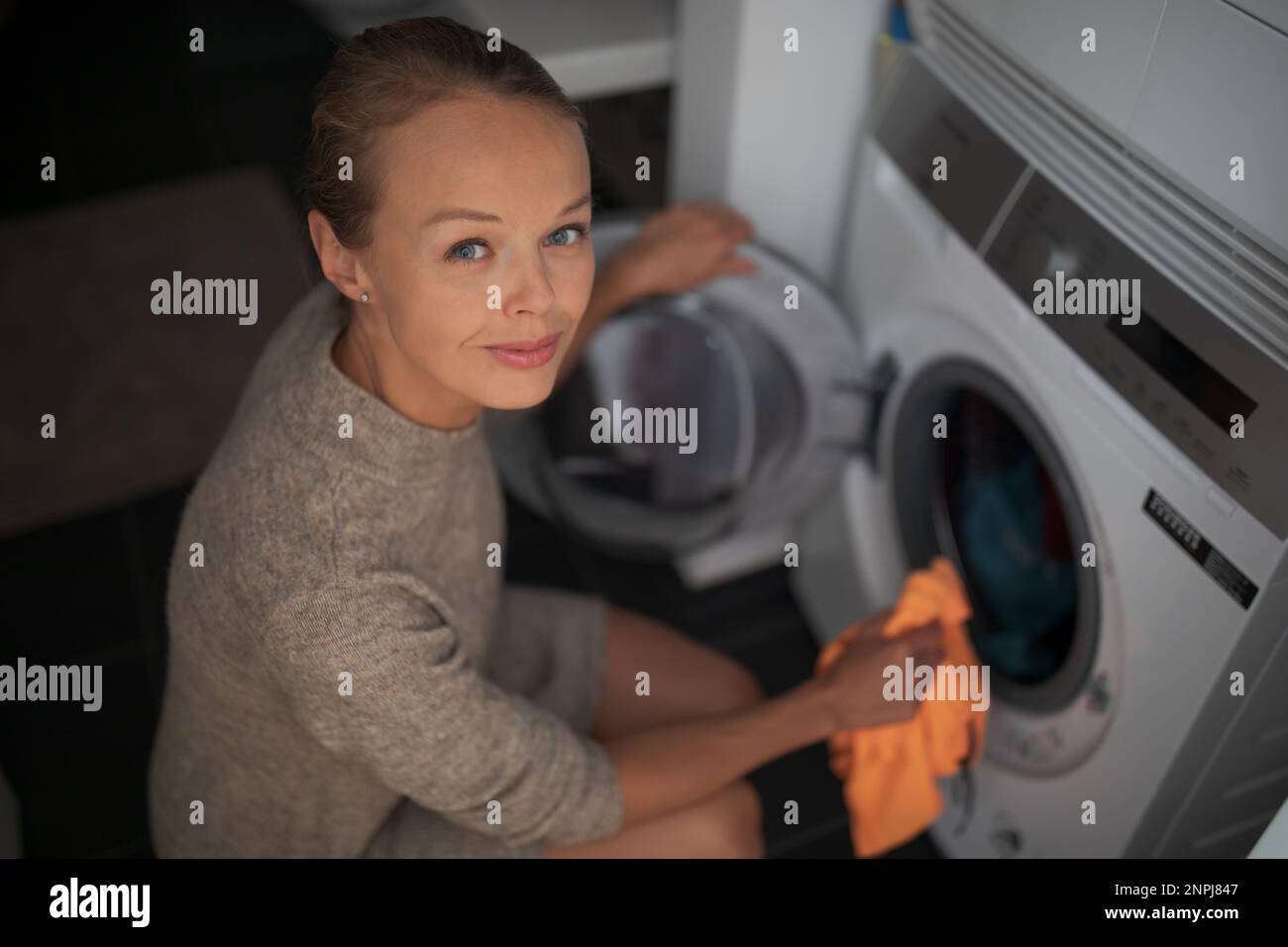 Pretty, young woman doing laundry at home. Choosing carefully the ...