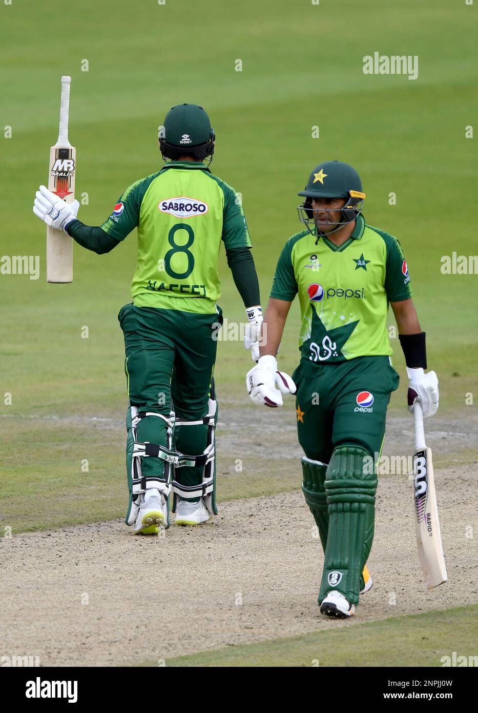 Pakistan's Mohammad Hafeez, left, raises his bat to celebrate scoring ...