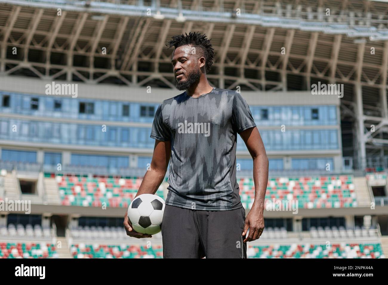 confident black football player holding the ball in his hand at the ...