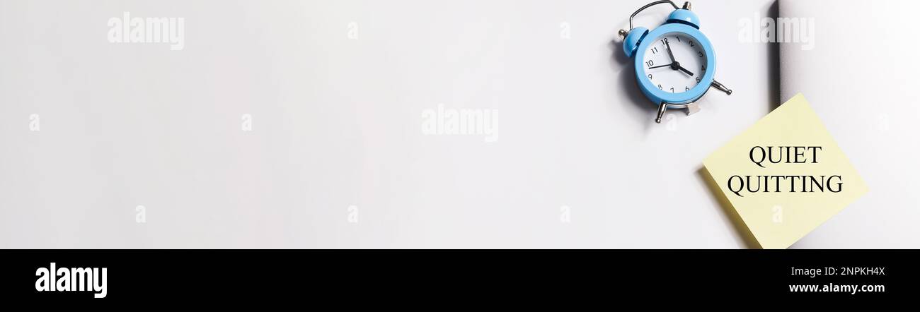 quote 'Quiet quitting' on yellow sticker on computer with clock . work ...