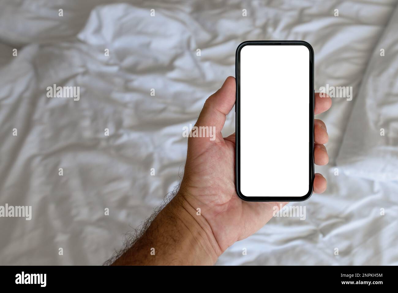 Male tourist in hotel bedroom holding smartphone with blank mockup ...