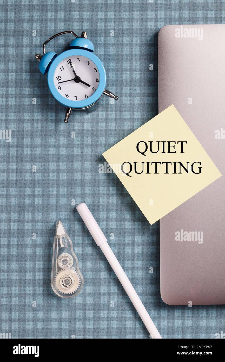 quote 'Quiet quitting' on yellow sticker on computer with clock and ...