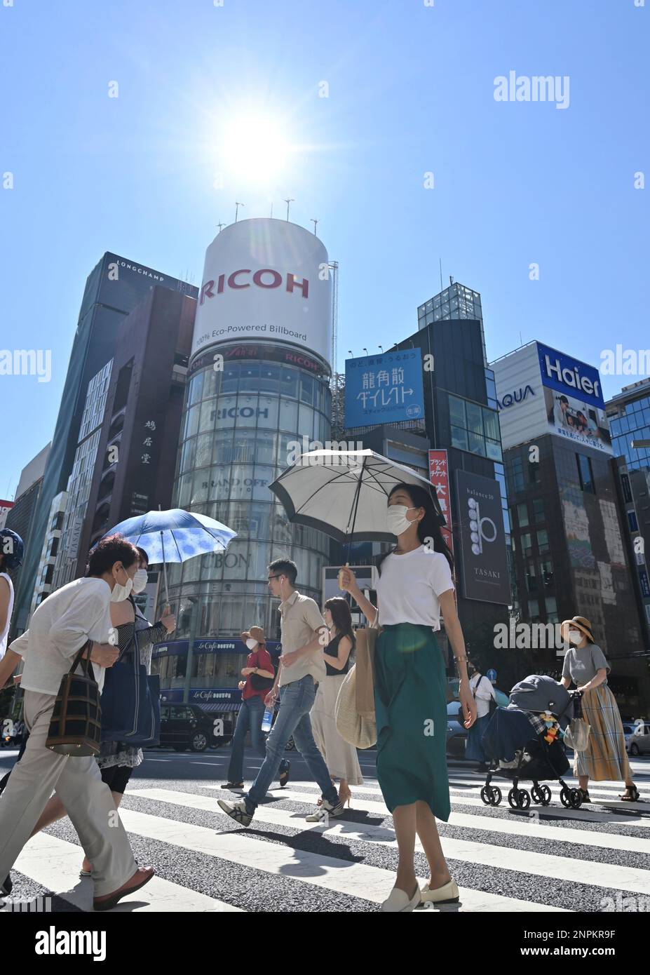 People wearing masks walk in strong sunlight at Ginza distrct in Tokyo ...