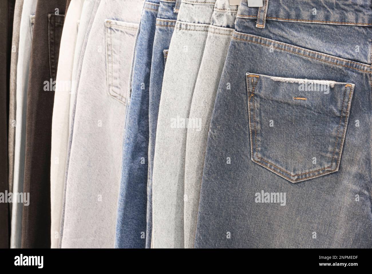 Many jeans hanging on arack. Row of pants denim jeans hanging in closet ...