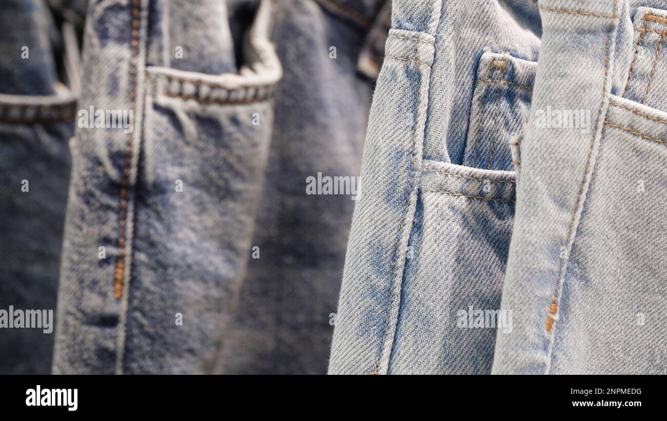 Many jeans hanging on arack. Row of pants denim jeans hanging in closet ...