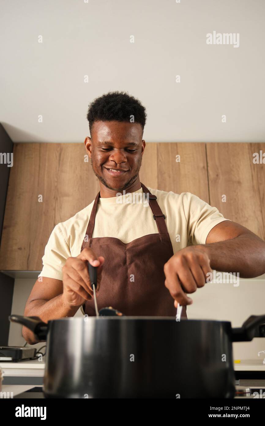 Young black cooking in a big pot Stock Photo - Alamy