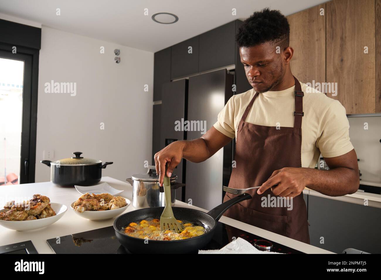 Young black man frying plantains slices Stock Photo - Alamy