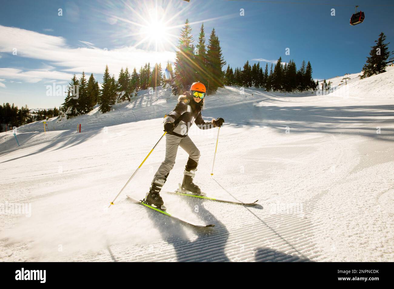 A single girl enjoys a sunny winter day of skiing, dressed in full snow ...