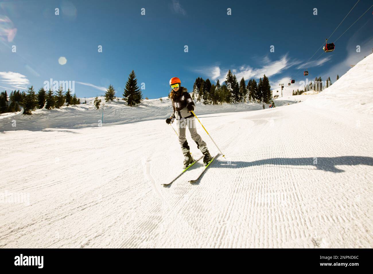 A single girl enjoys a sunny winter day of skiing, dressed in full snow ...