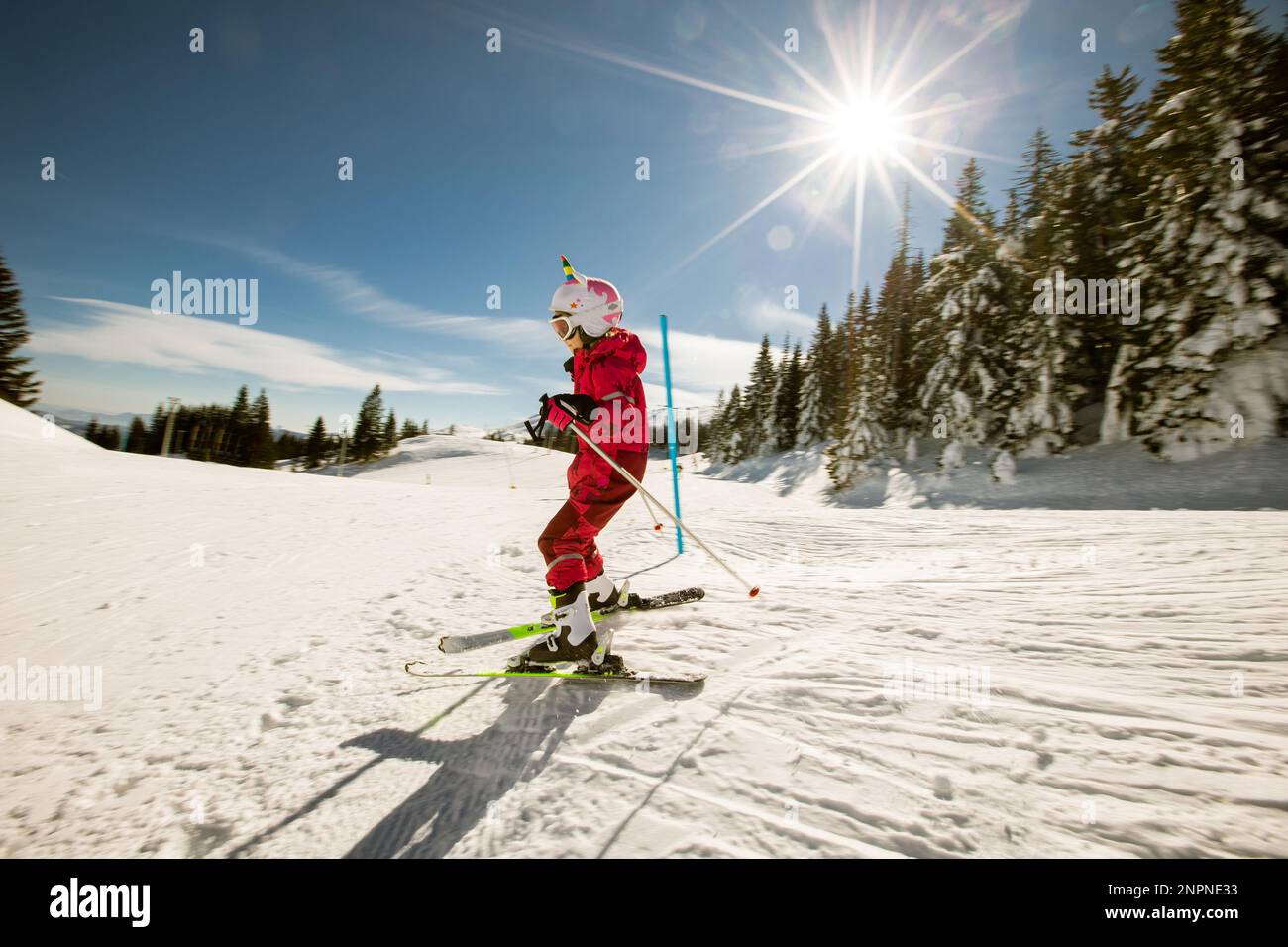 A single girl enjoys a sunny winter day of skiing, dressed in full snow ...