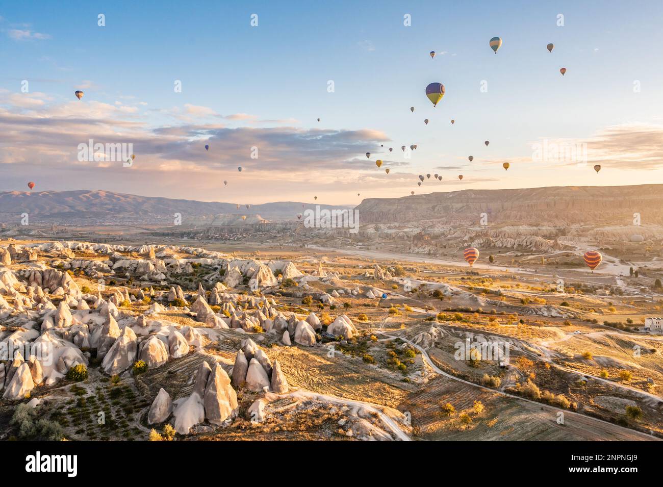 Balloons in sunrise flying over rock formations in Cappadocia, Turkey ...