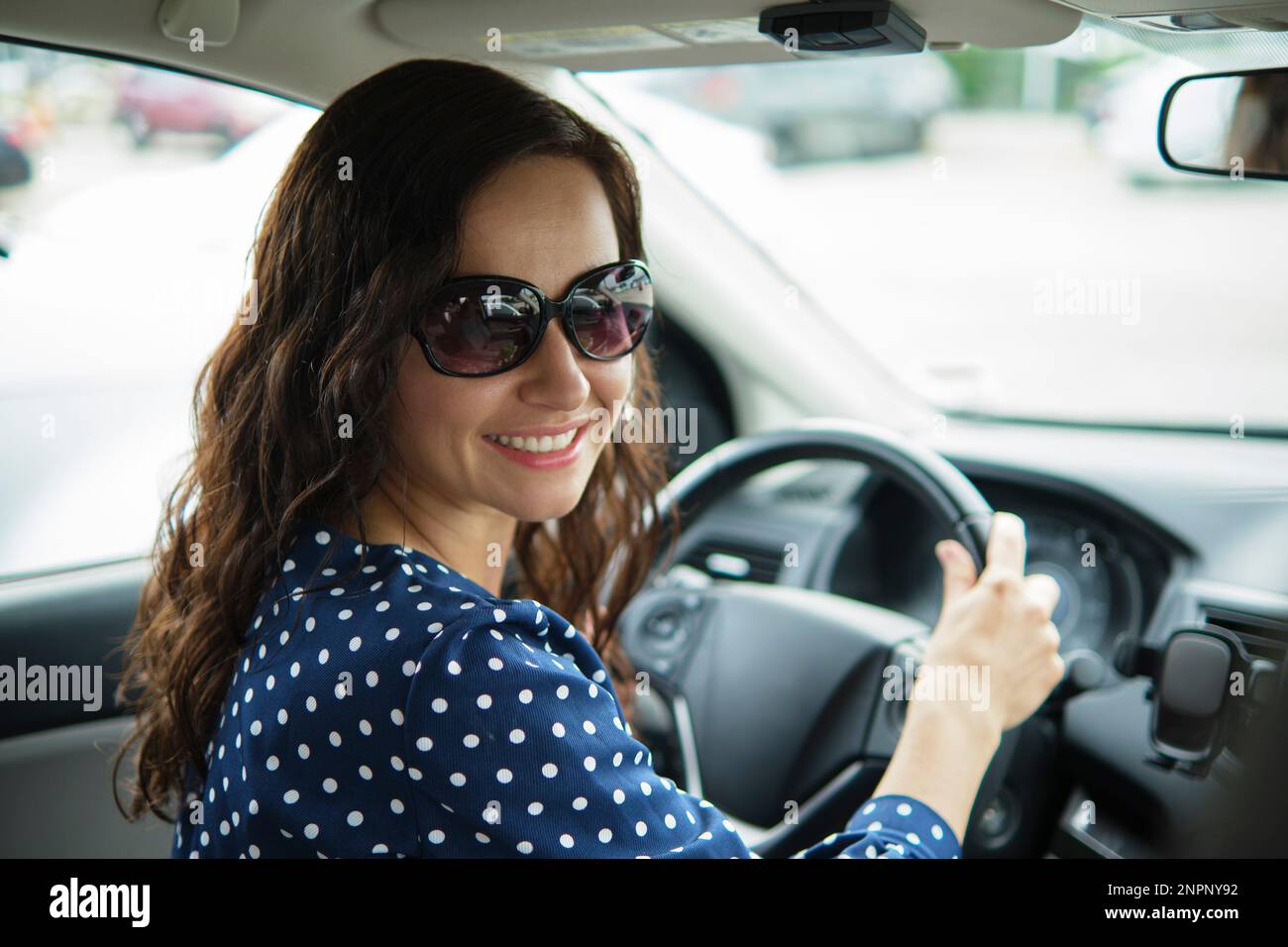 Young stylish woman driver sitting behind steering wheel of her car ...