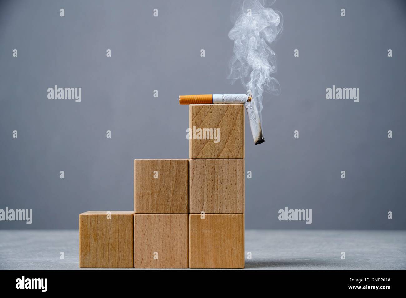 Top wooden ladder of cubes lies a broken, smoking cigarette.Concept ...