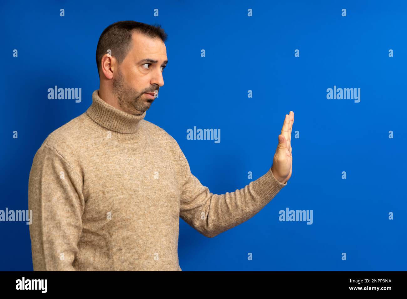 Strict bearded hispanic man showing stop sign, standing with frowning ...