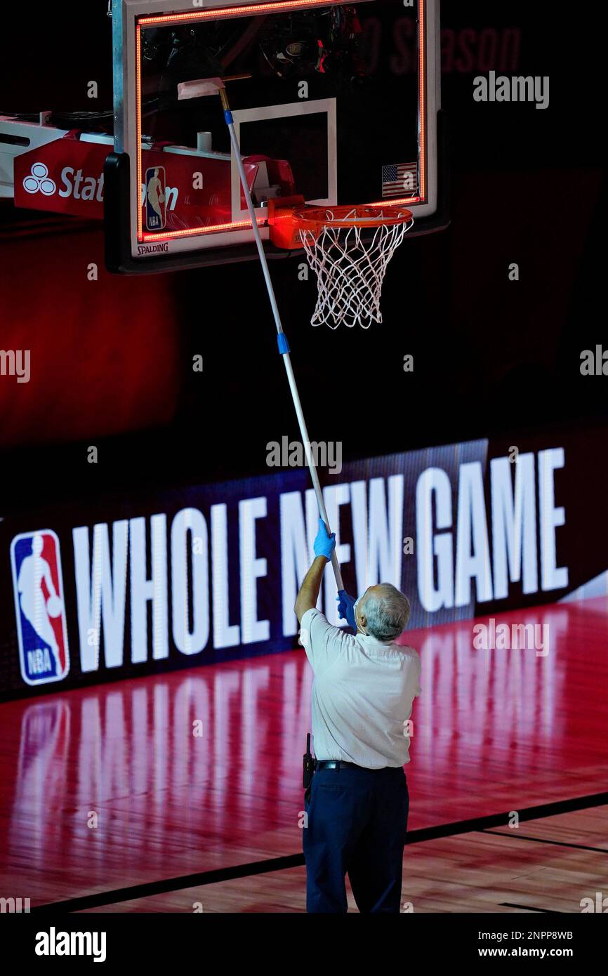 A worker cleans a backboard after an NBA basketball game between the ...