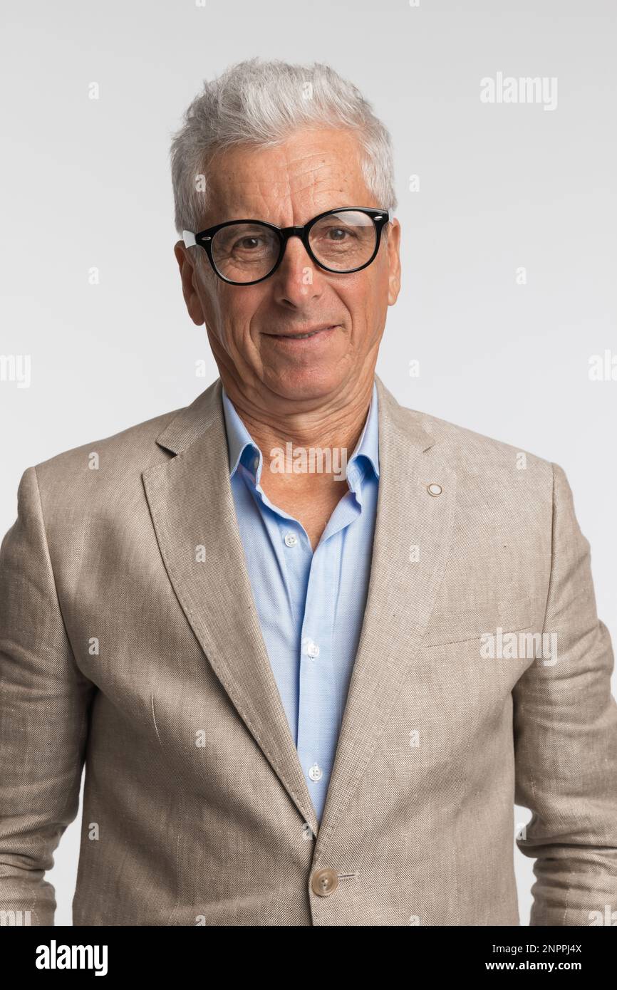 portrait of elegant man in his 60s wearing beige suit and glasses and ...
