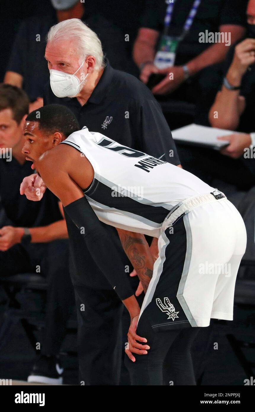 San Antonio Spurs head coach Gregg Popovich in a mask talks with guard ...