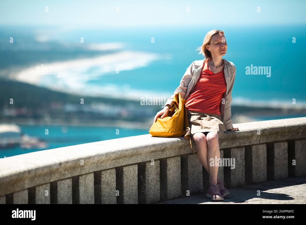 A woman sits on an observation deck on the shore of the Atlantic Ocean ...