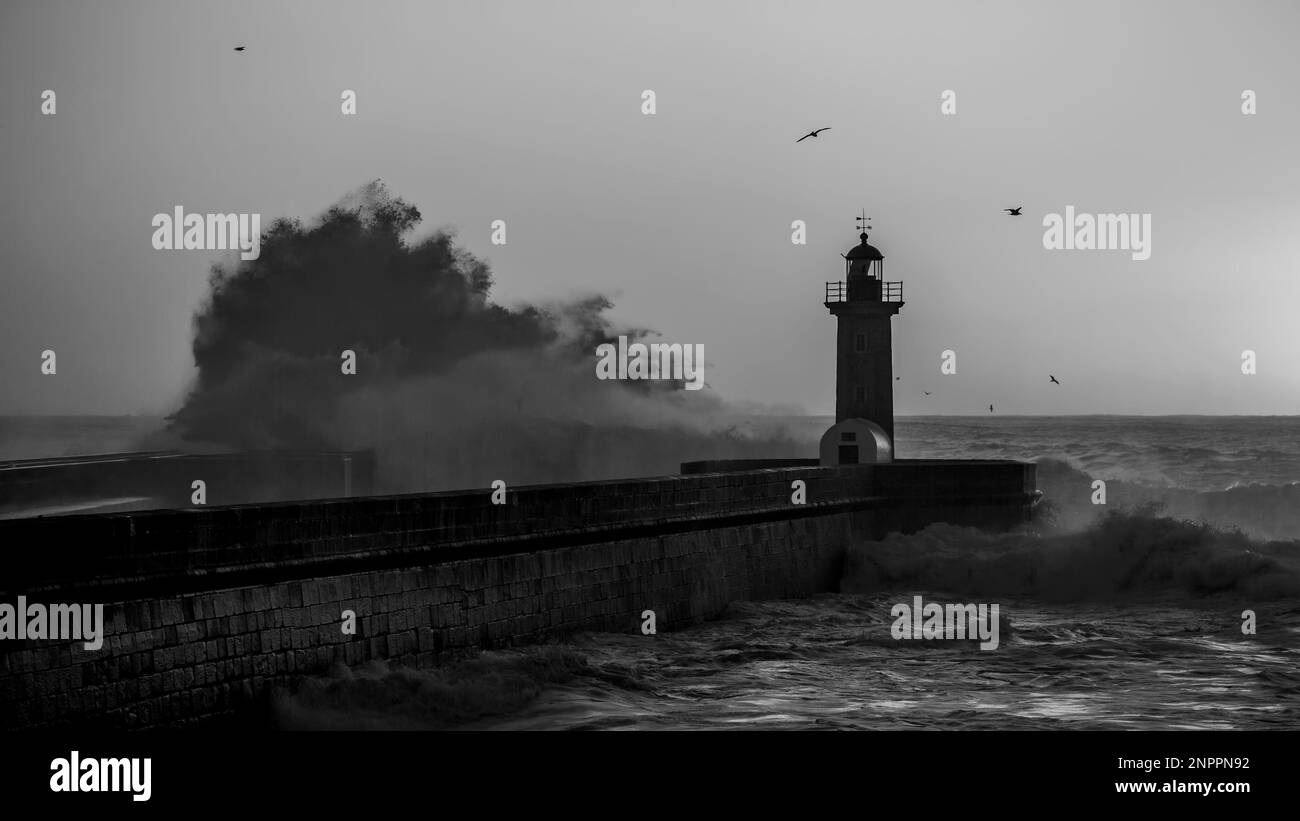 Lighthouse with a huge wave on the Atlantic, Porto, Portugal. Black and ...