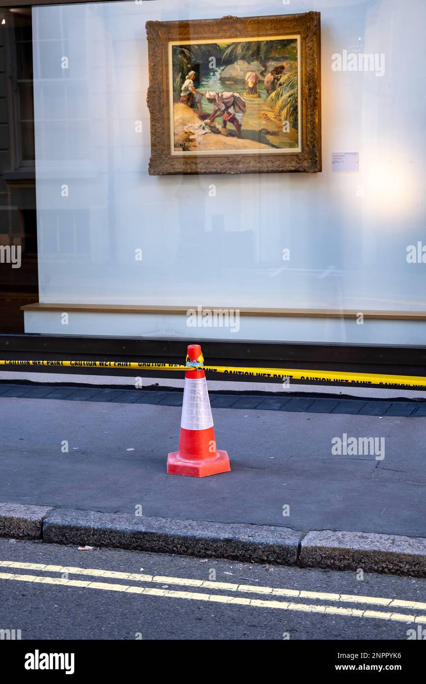 Caution Wet Paint sign on yellow tape cordoning off a small area by ...