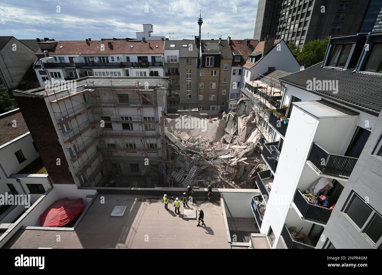 Firefighters stand in front of the collapsed building and scaffolding ...
