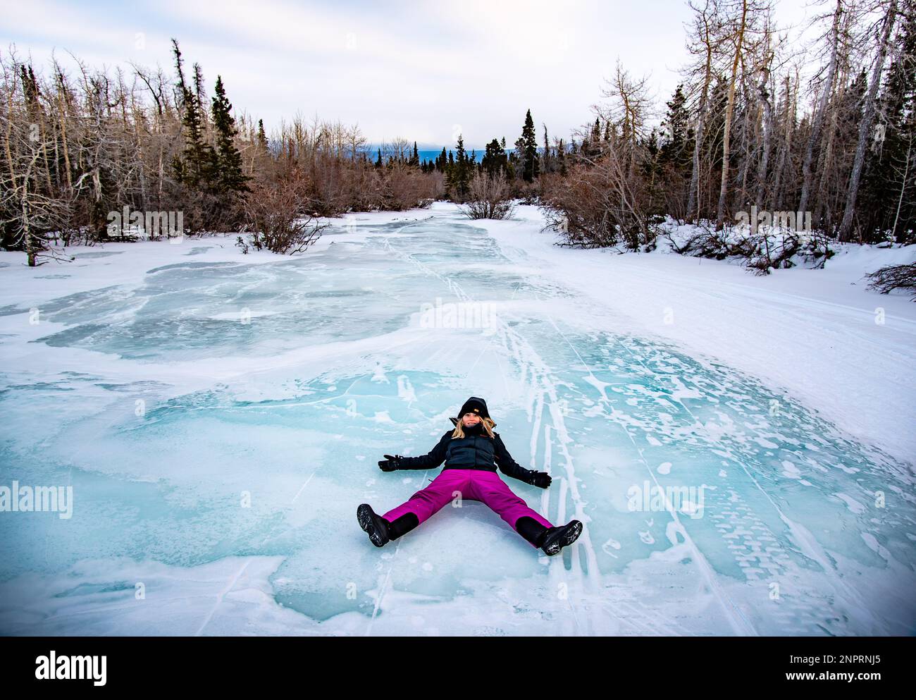 Woman laying on frozen river in full winter clothing. Taken in the ...