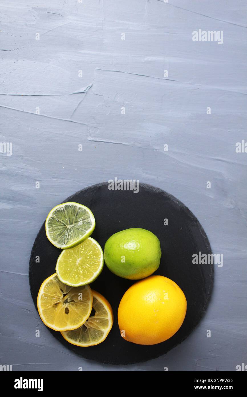 still life citrus fruits orange lemon lime lie on a tray on a gray ...